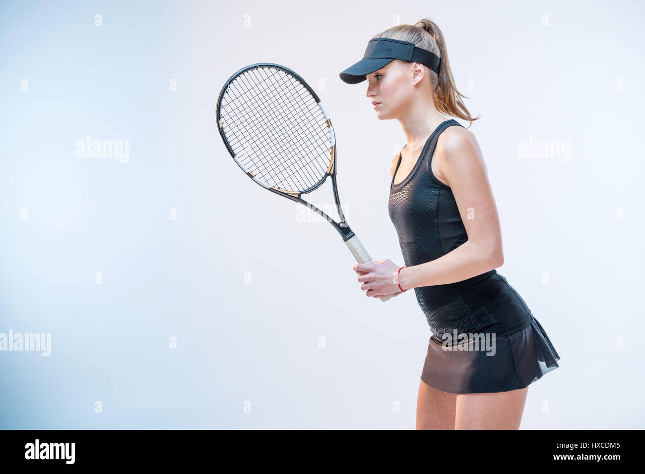 side view of concentrated young woman in tennis uniform with racket in ...
