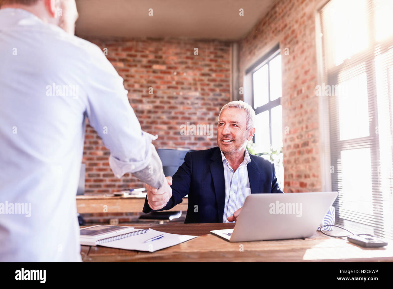 Businessmen shaking hands at laptop Stock Photo - Alamy