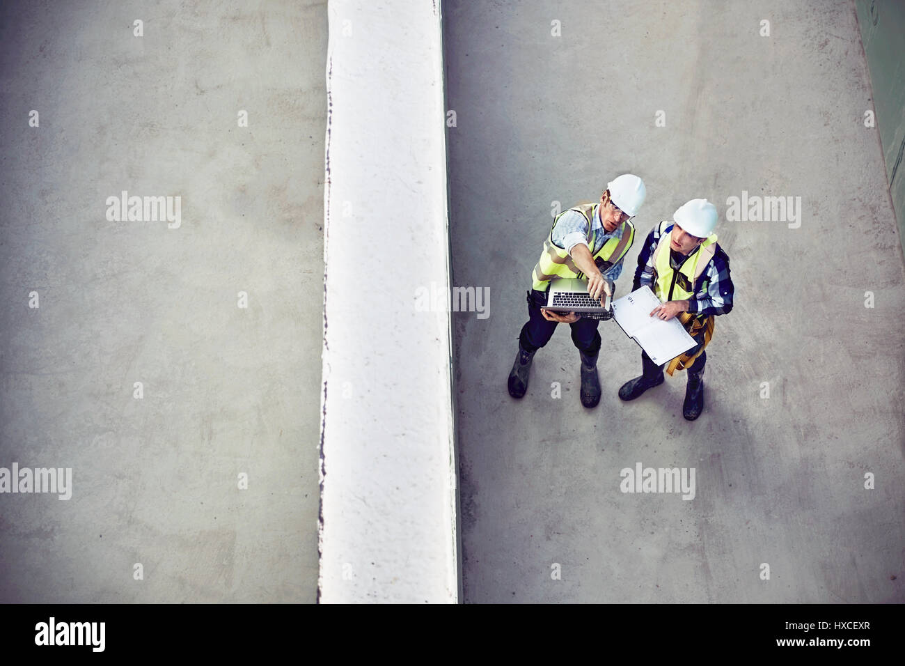 Construction worker and engineer with laptop talking at construction ...