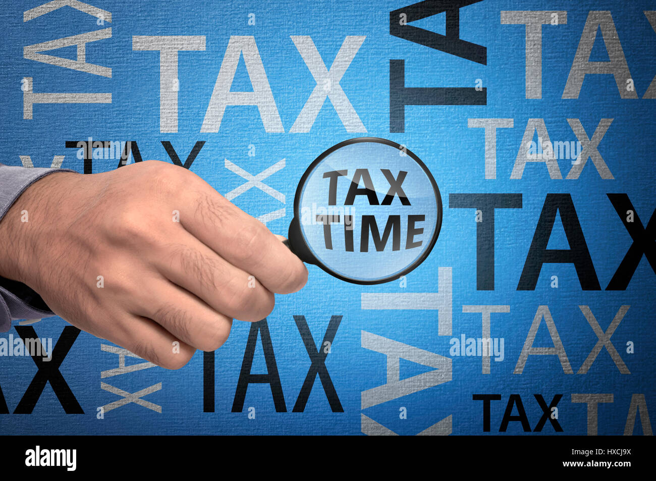 Business hand holding magnifying glass over TAX TIME text on blue ...