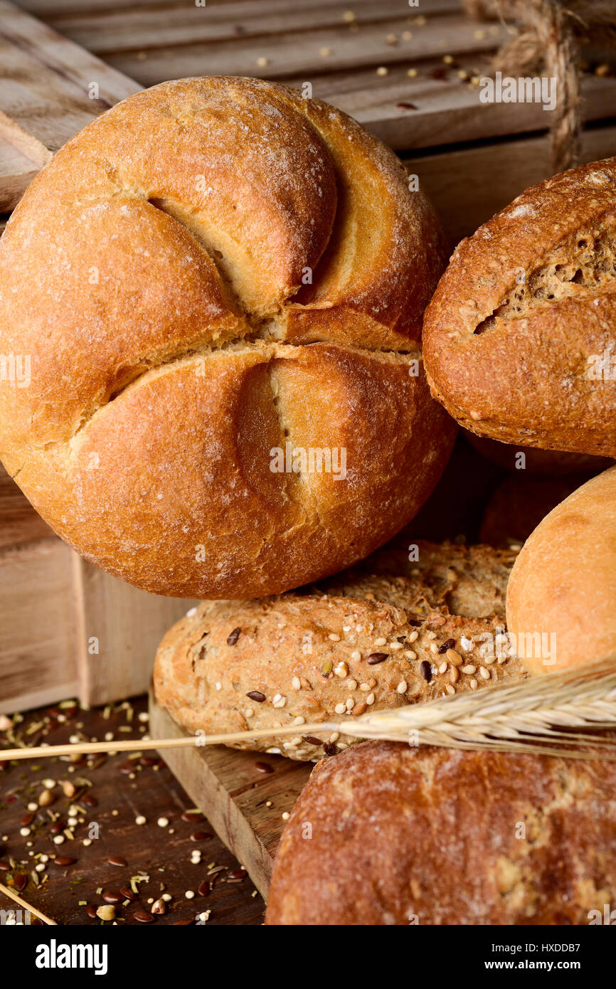 closeup of an assortment of different bread rolls and some wheat ears ...