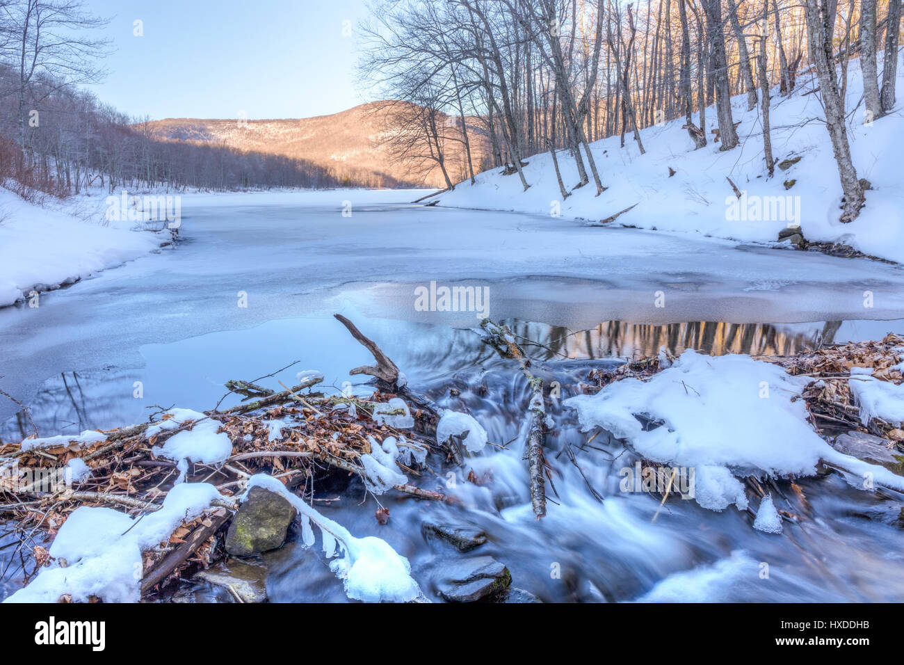 Reflections and ripples in the water that flows out of partially frozen ...