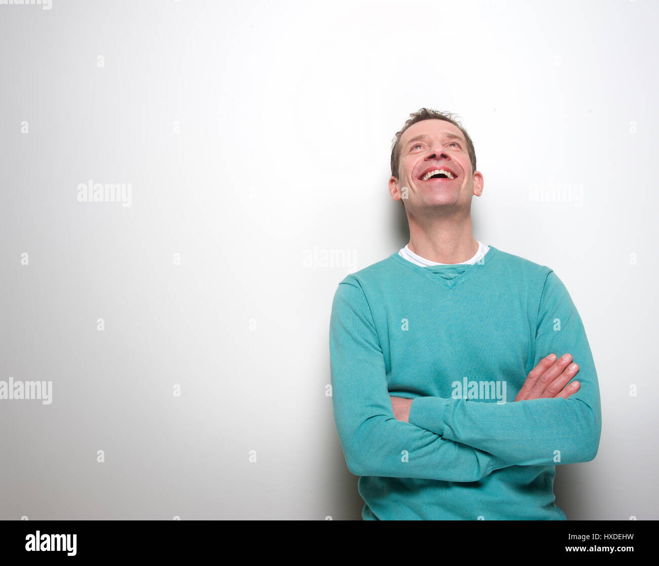 Portrait of a middle aged man laughing with arms crossed and looking up ...