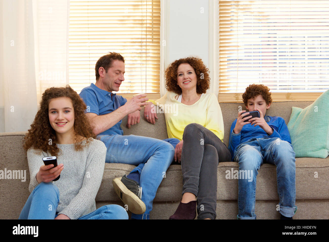 Portrait of a happy family relaxing at home with daughter holding remote control Stock Photo - Alamy