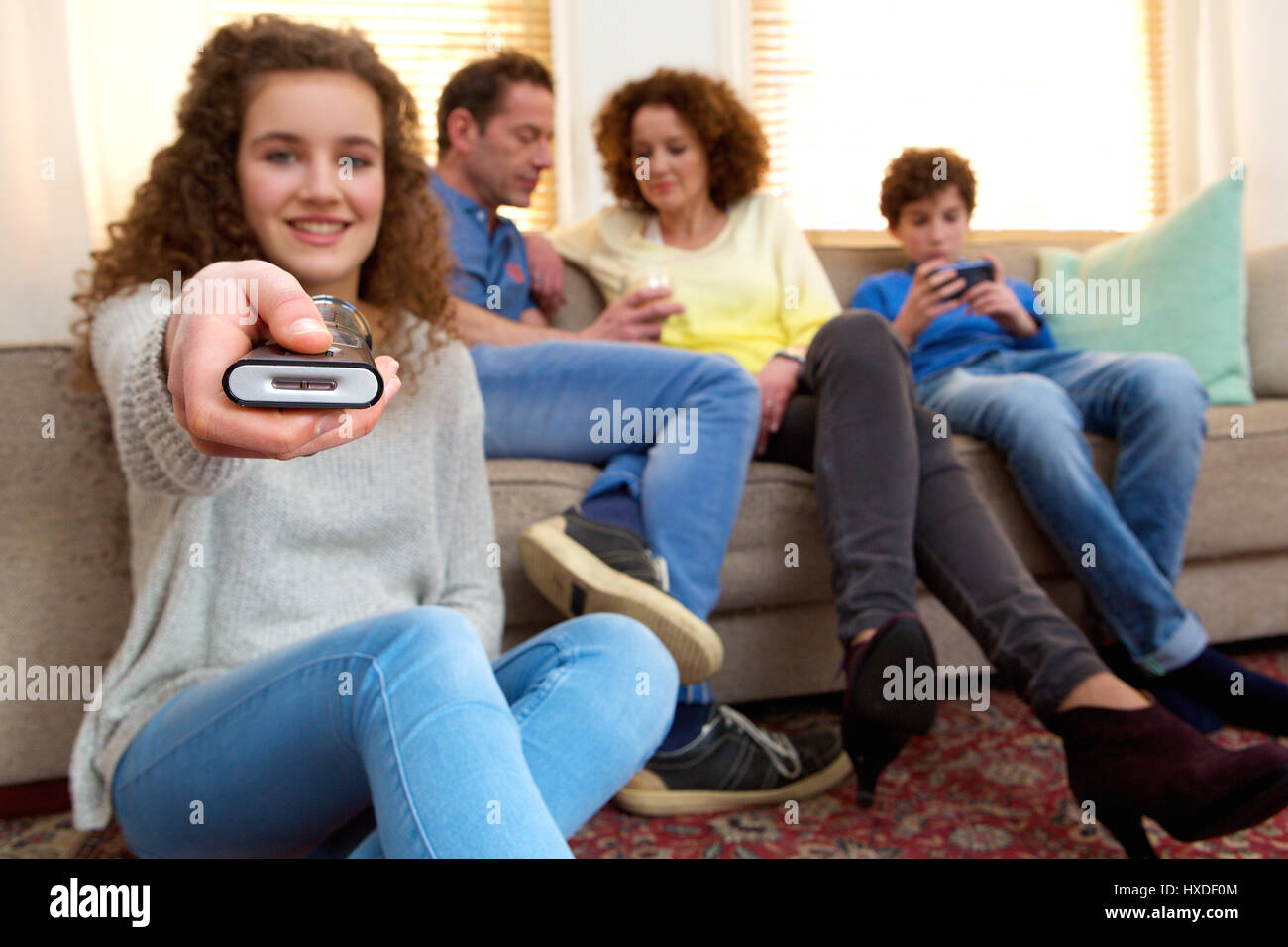 Portrait of a happy girl holding remote control with family in the ...
