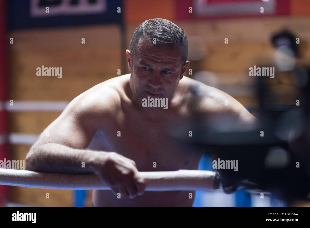 muscular professional kick boxer resting on the ropes in the corner of ...