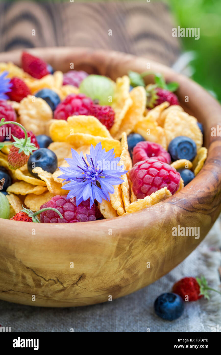 Closeup of berry fruits with cornflakes in wooden bowl Stock Photo - Alamy