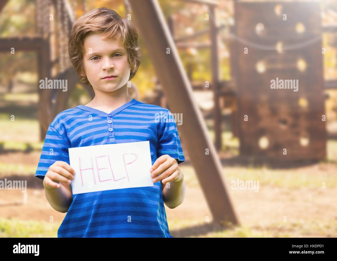 Digital composite of Sad boy holding help sign against playground Stock ...