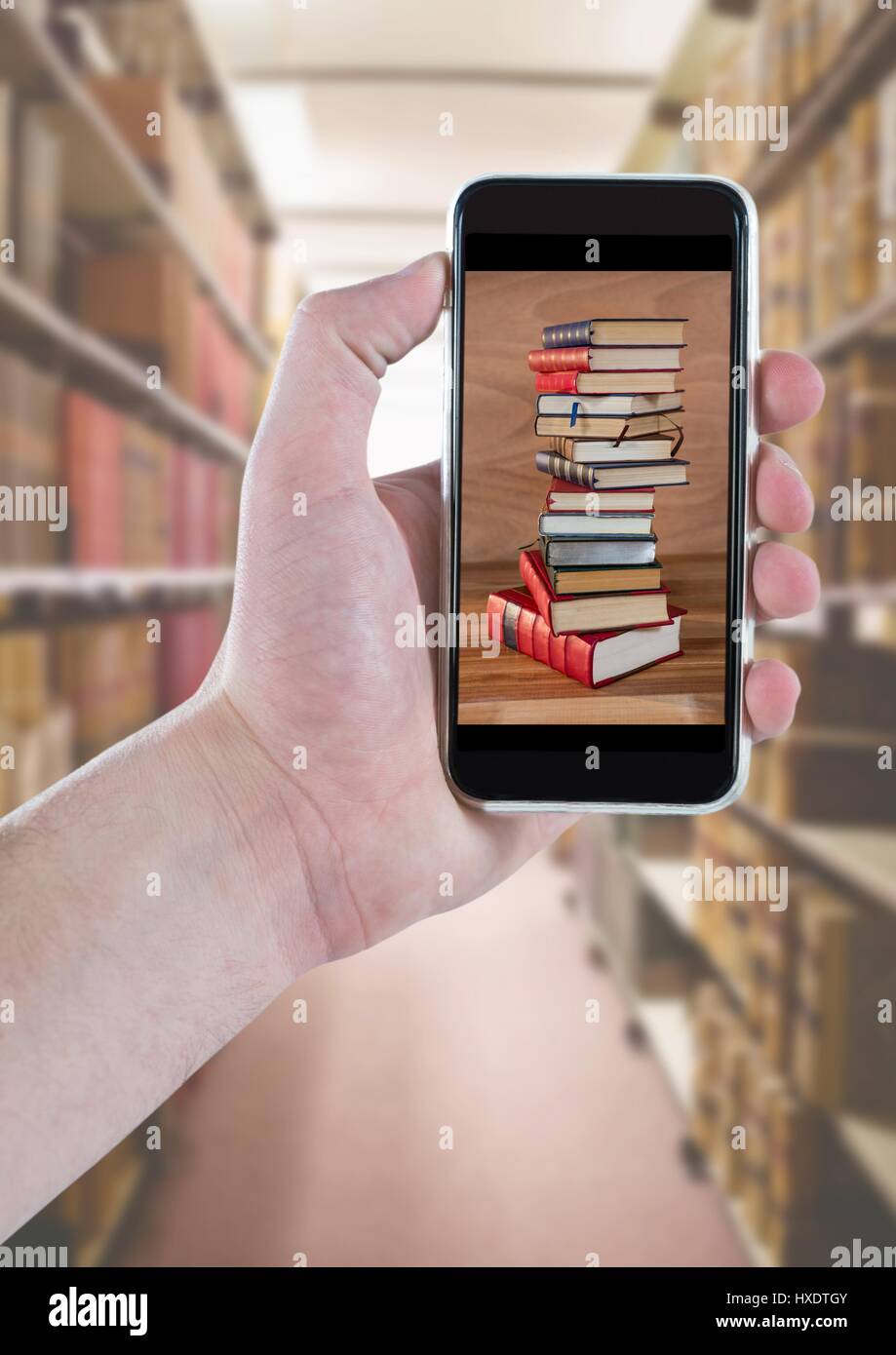 Digital composite of Hand with phone showing book pile against blurry ...