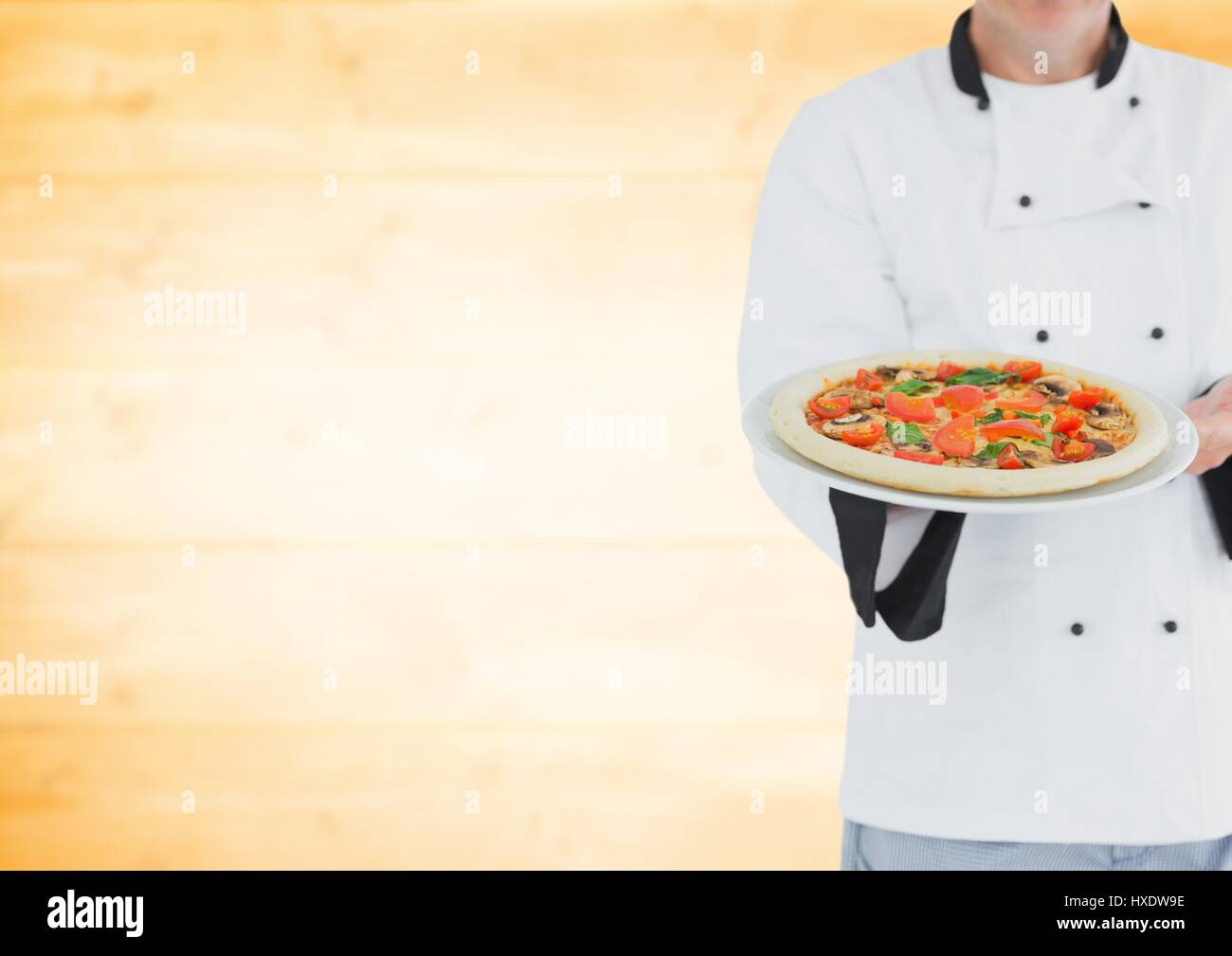 Digital composite of Chef with pizza against blurry yellow wood panel ...