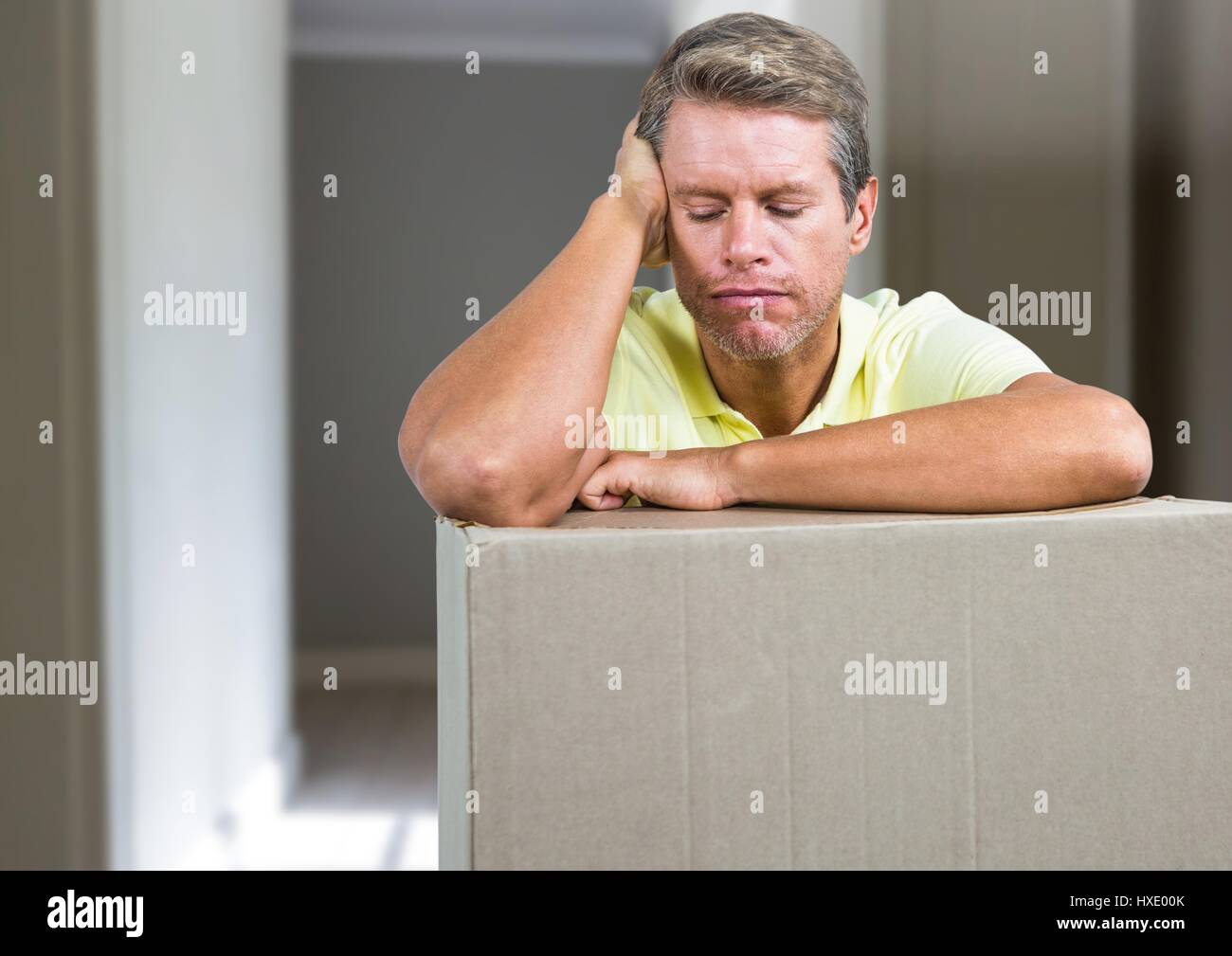 Digital composite of Sad man with cardboard box parcel against hall ...
