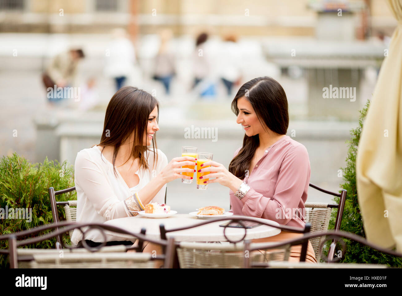 Two female friends sitting outside in a cafe and have fun Stock Photo ...