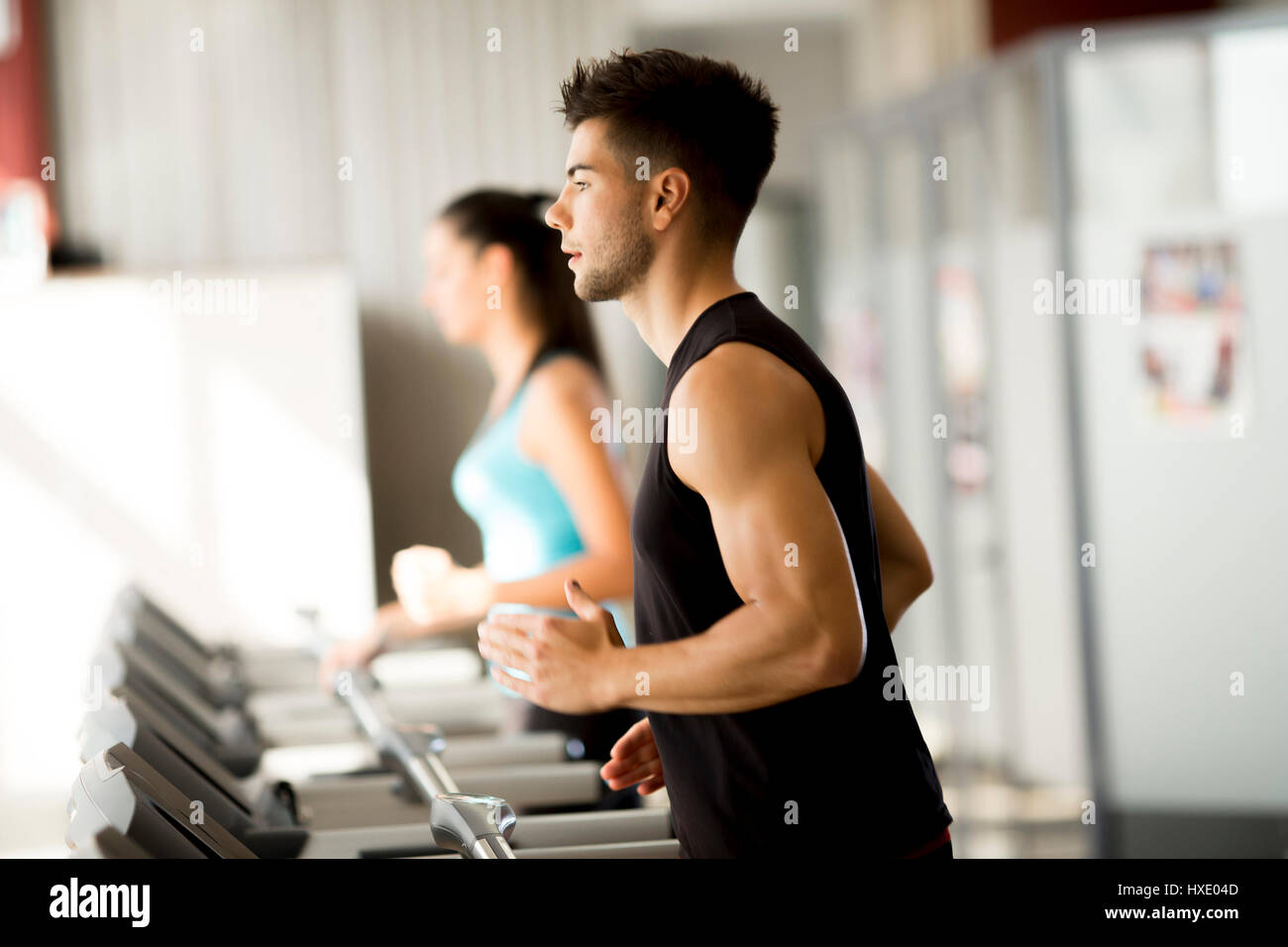 Side view full length of young man in sportswear running on treadmill ...