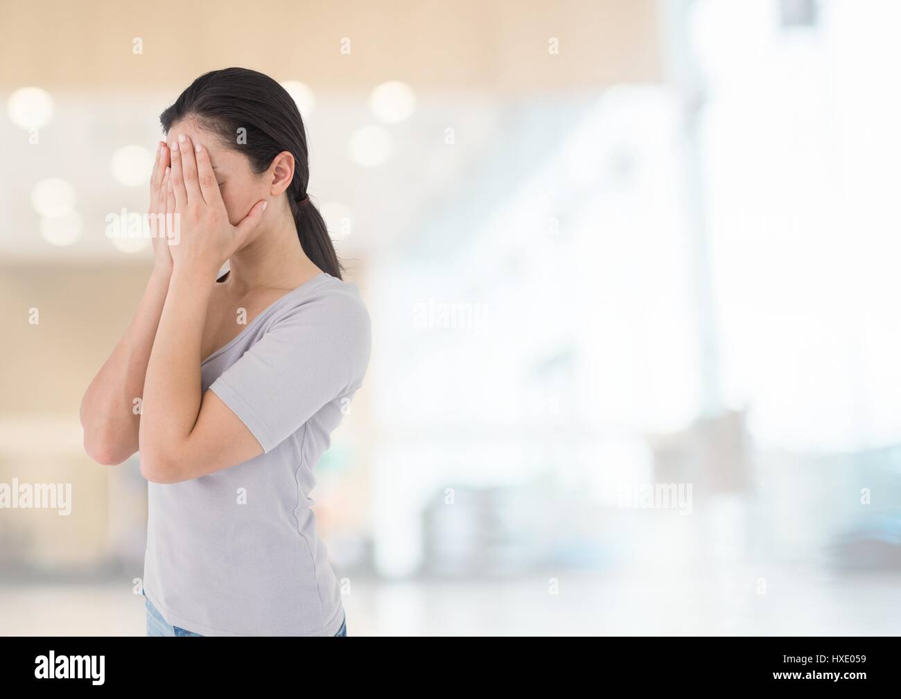 Digital composite of Sad woman grief hands over face against bright ...