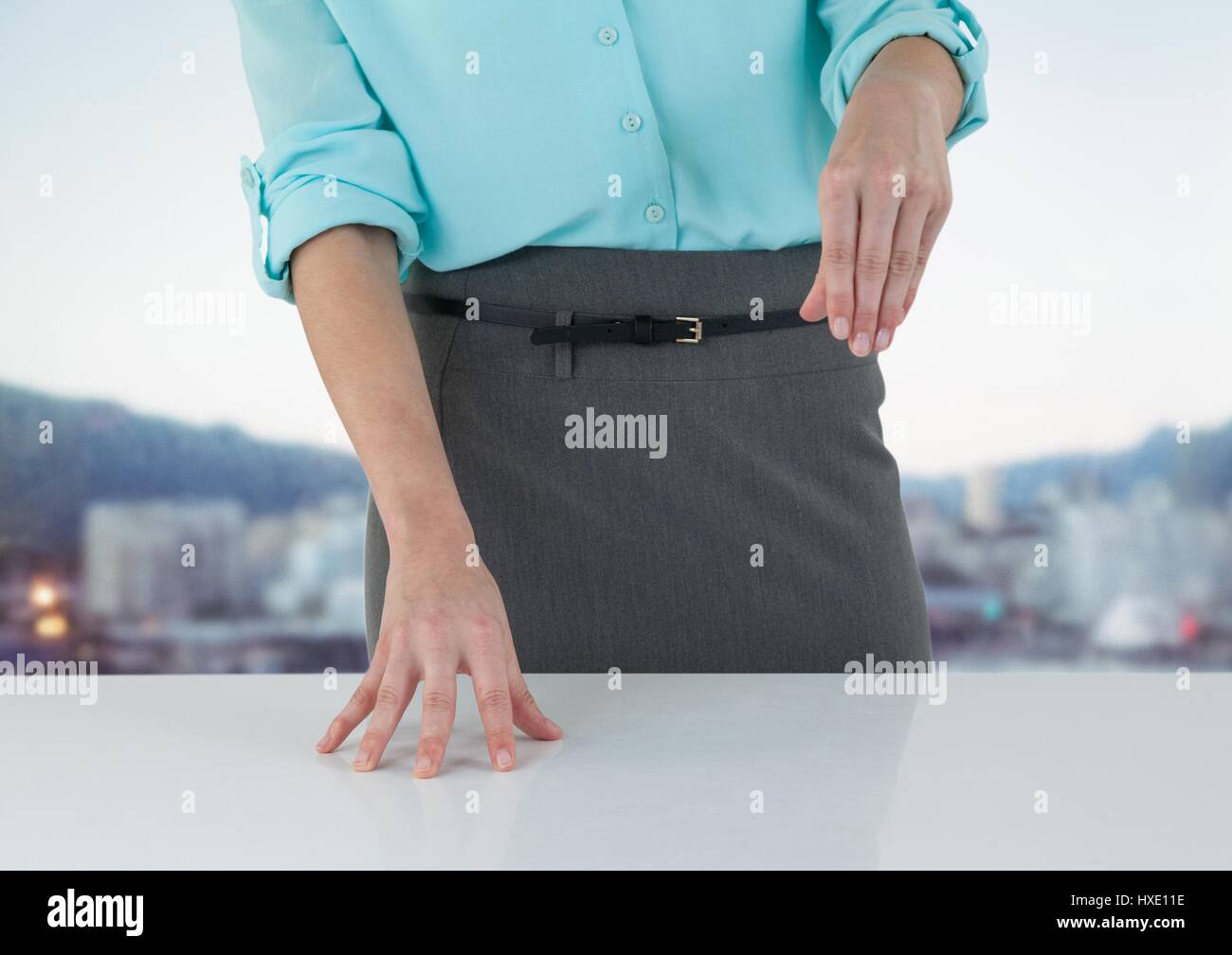 Digital composite of Business woman mid section at desk against blurry ...