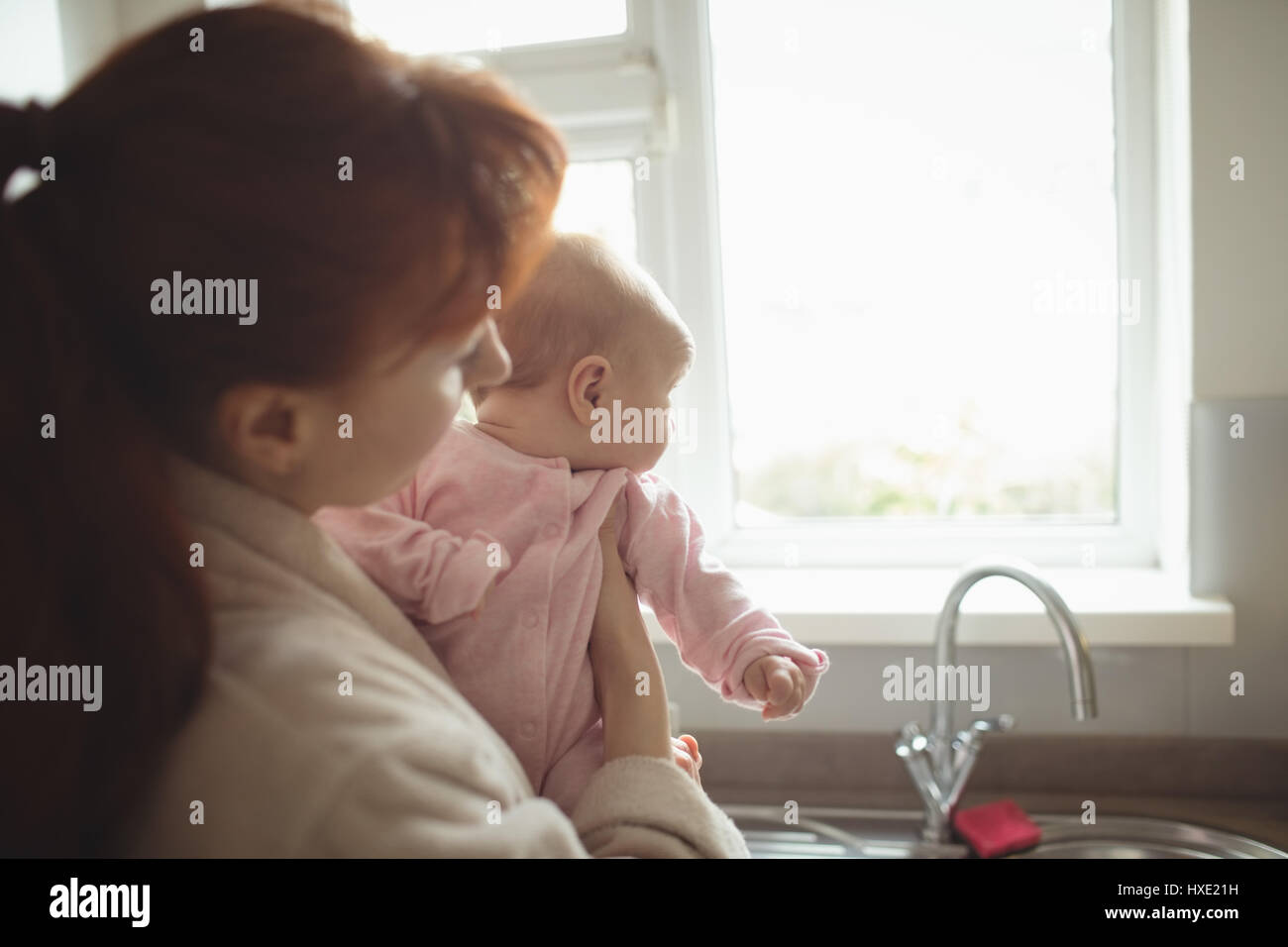 Mother and baby looking through kitchen window at home Stock Photo - Alamy