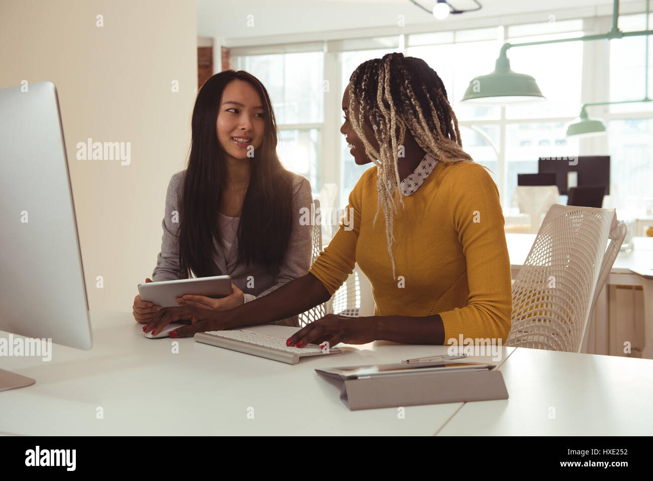 Two female executives working on computer at desk in office Stock Photo ...