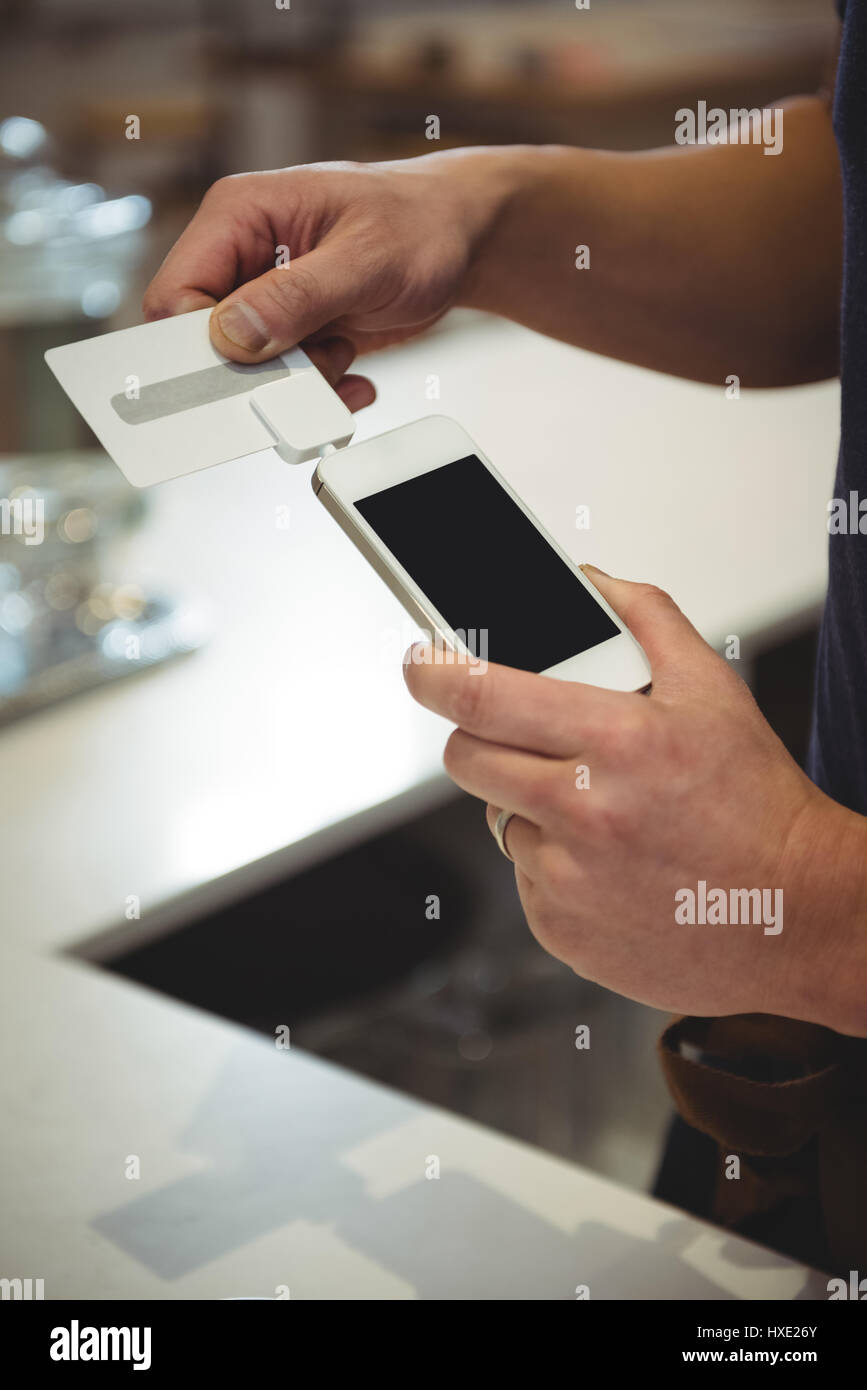 Cropped image of barista swiping credit card into device that is ...