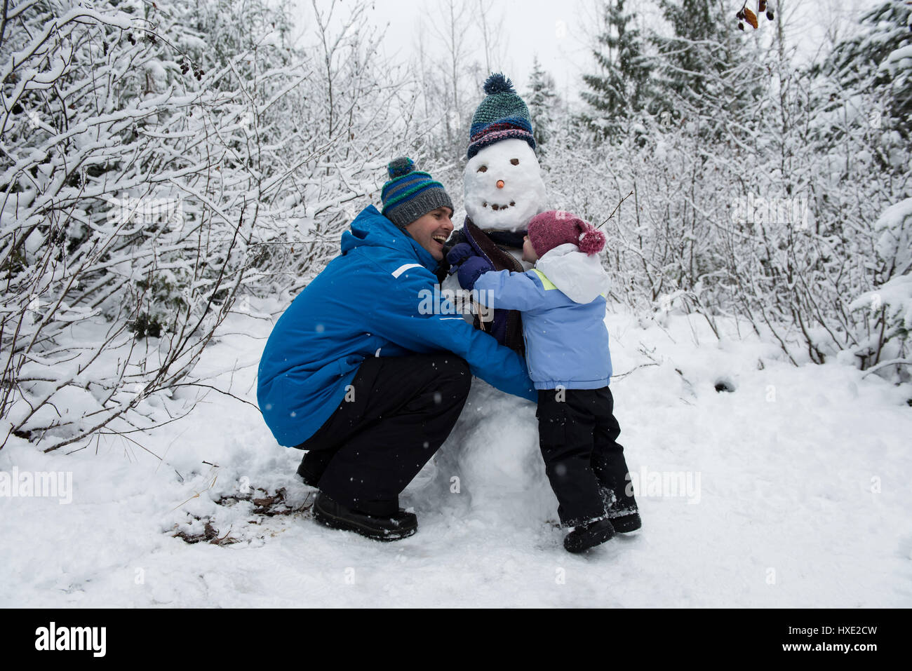 Cheerful father and daughter making snowman on beautiful snowy day ...