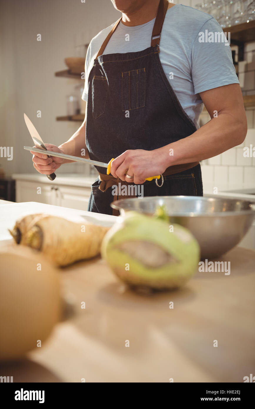 Mid section of male chef sharpening knife in commercial kitchen Stock ...