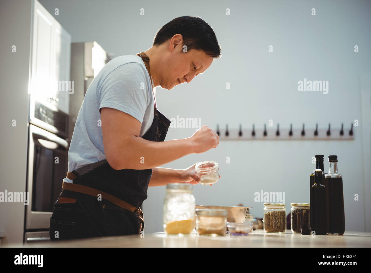 Side view of male chef with ingredients cooking in commercial kitchen ...