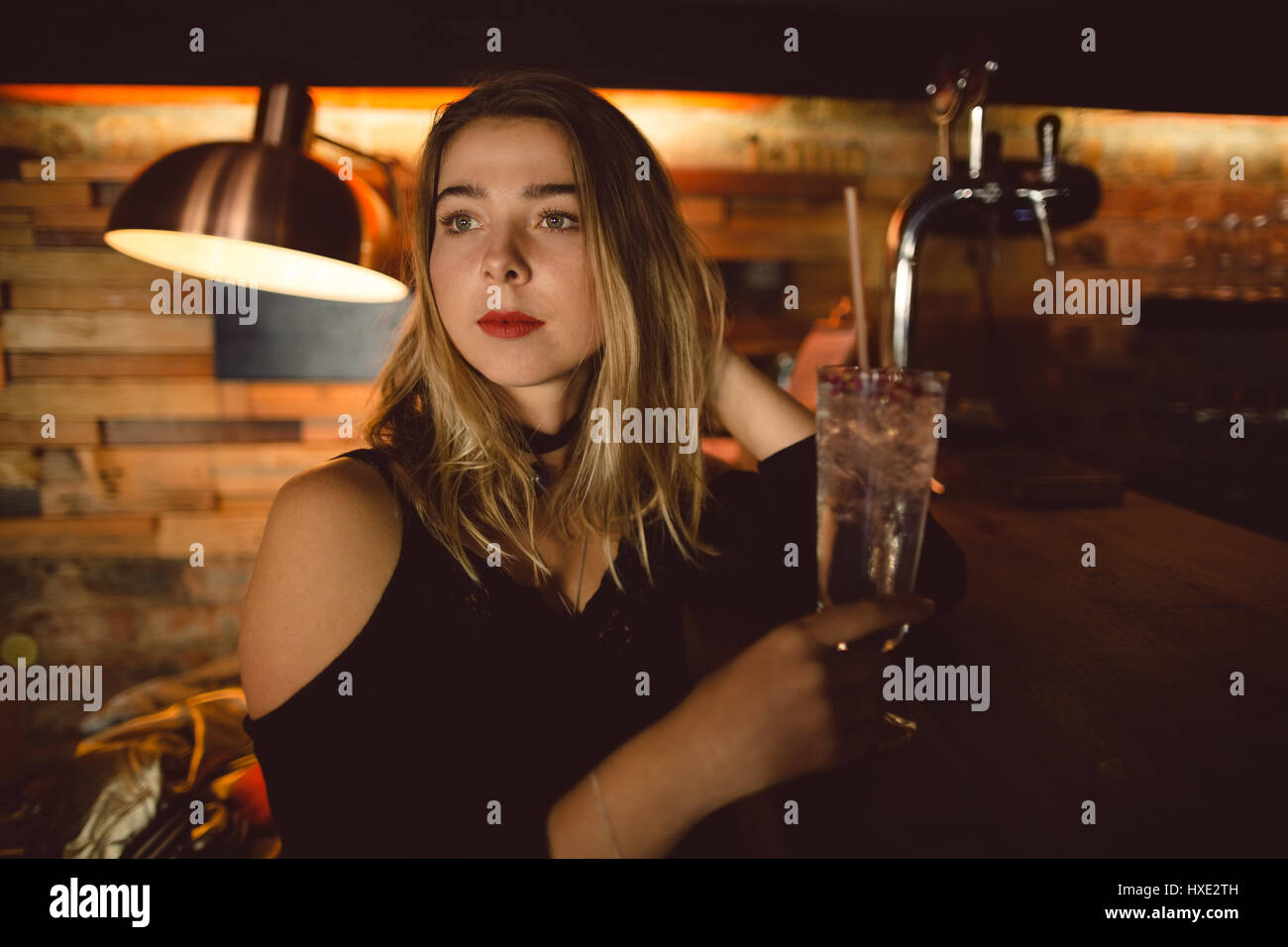 Beautiful woman having cocktail at counter in bar Stock Photo - Alamy