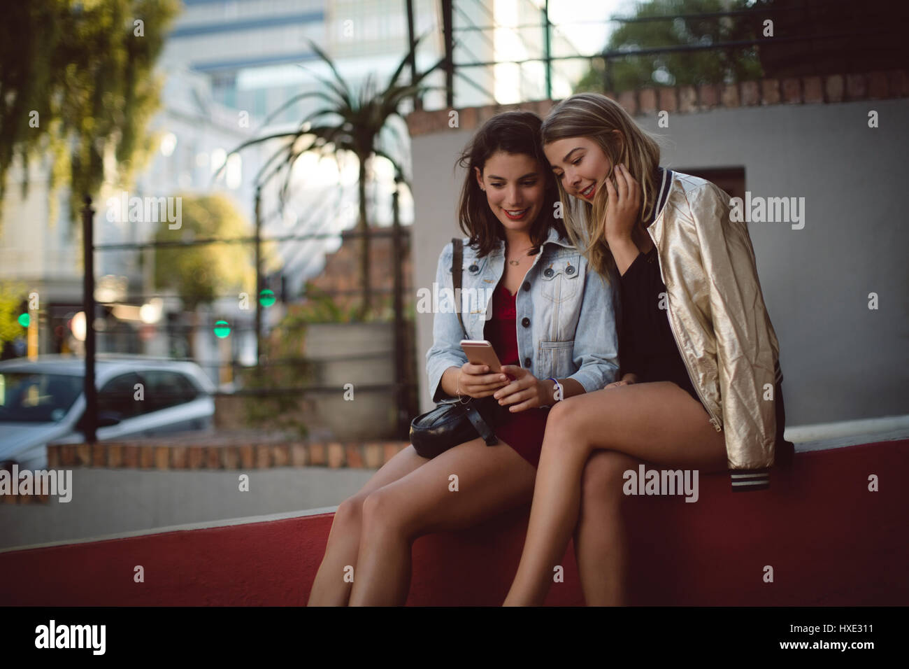 Happy friends using mobile phone Stock Photo - Alamy
