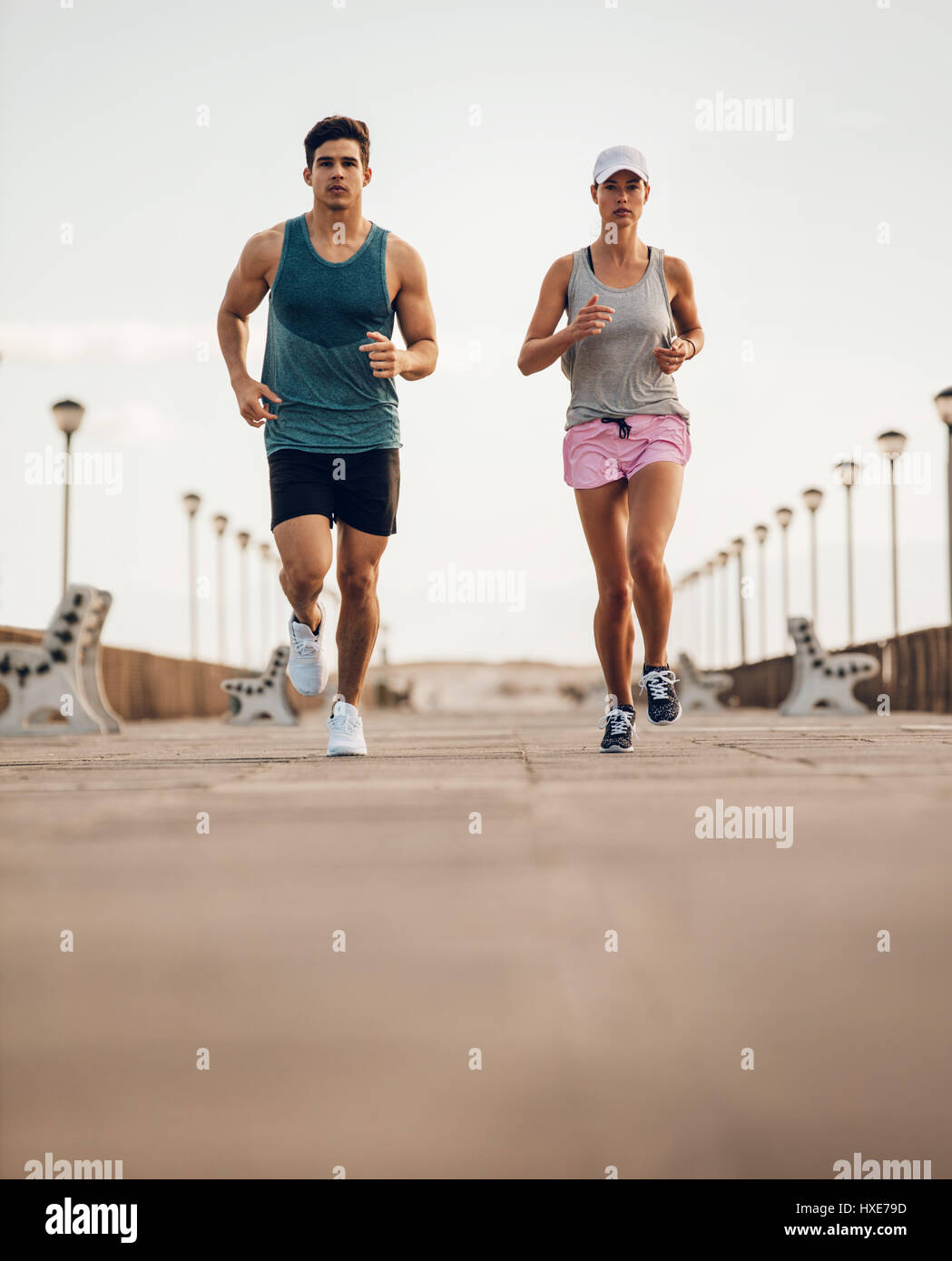 Two young people running on road. Couple of runners on morning run ...