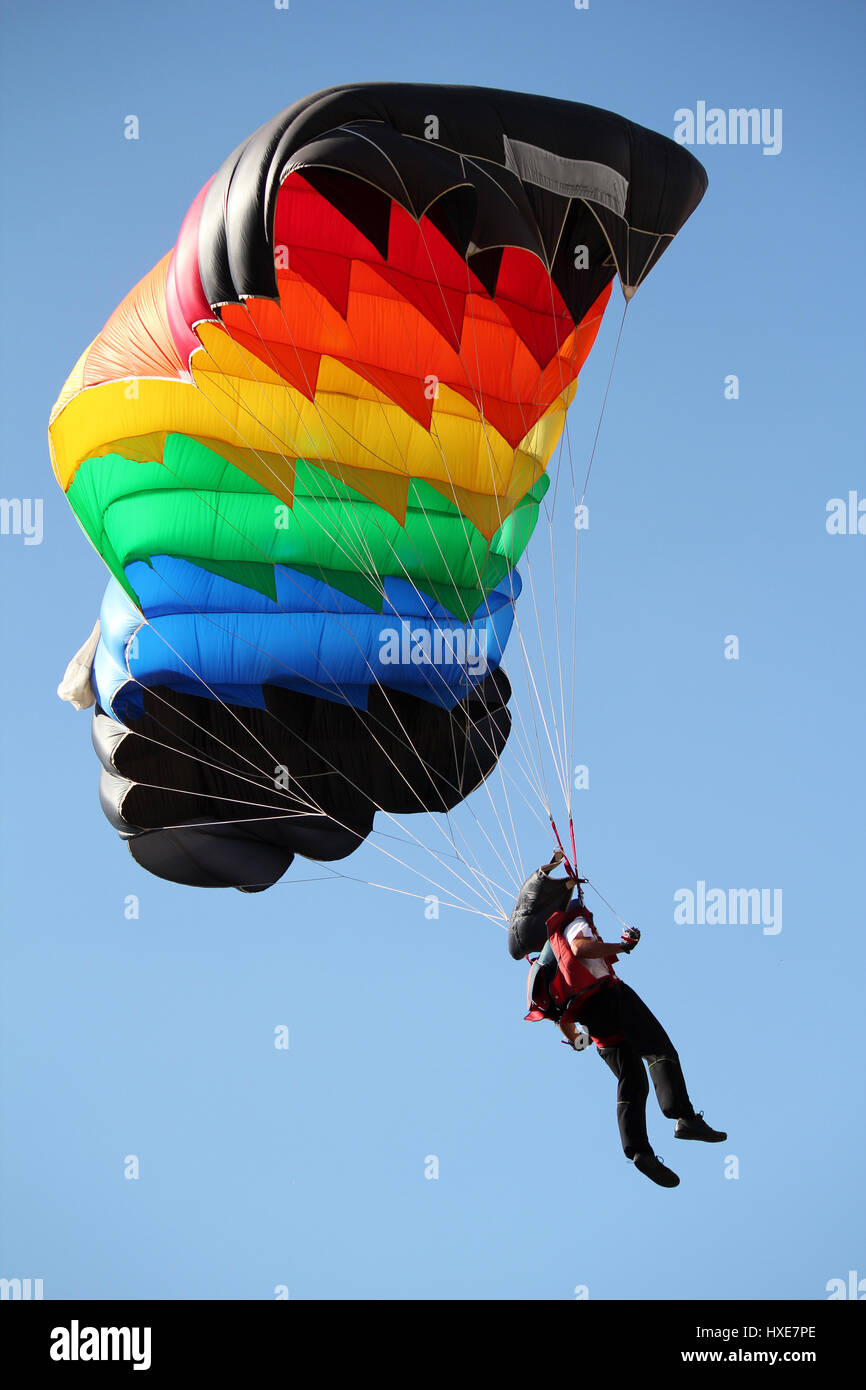parachutist with colorful parachute on blue sky Stock Photo - Alamy