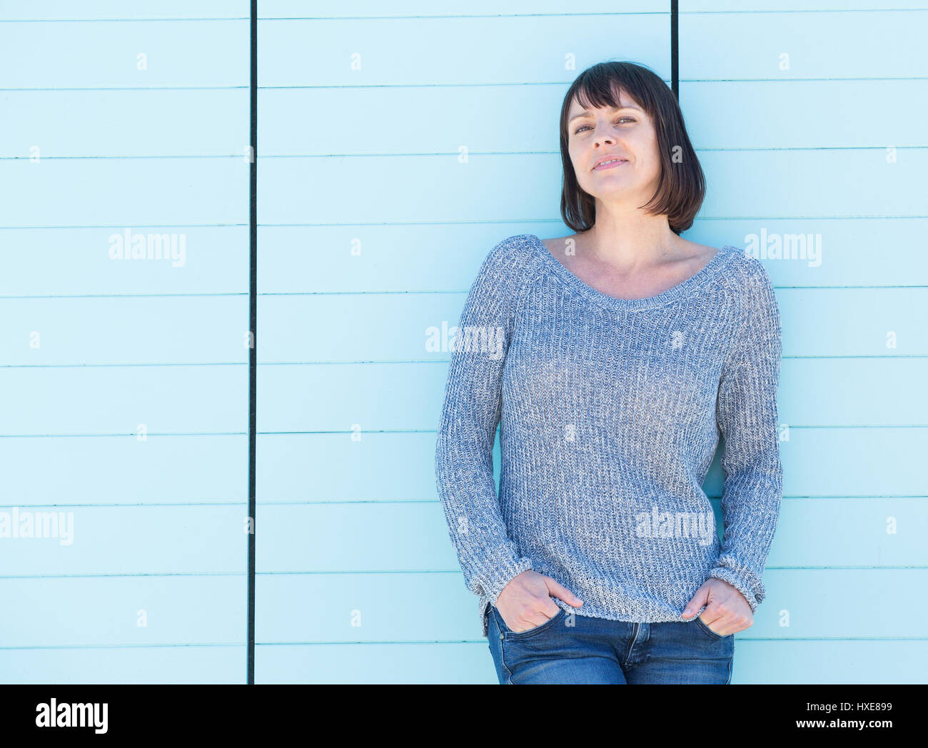 Portrait of a charming woman standing against blue background Stock ...