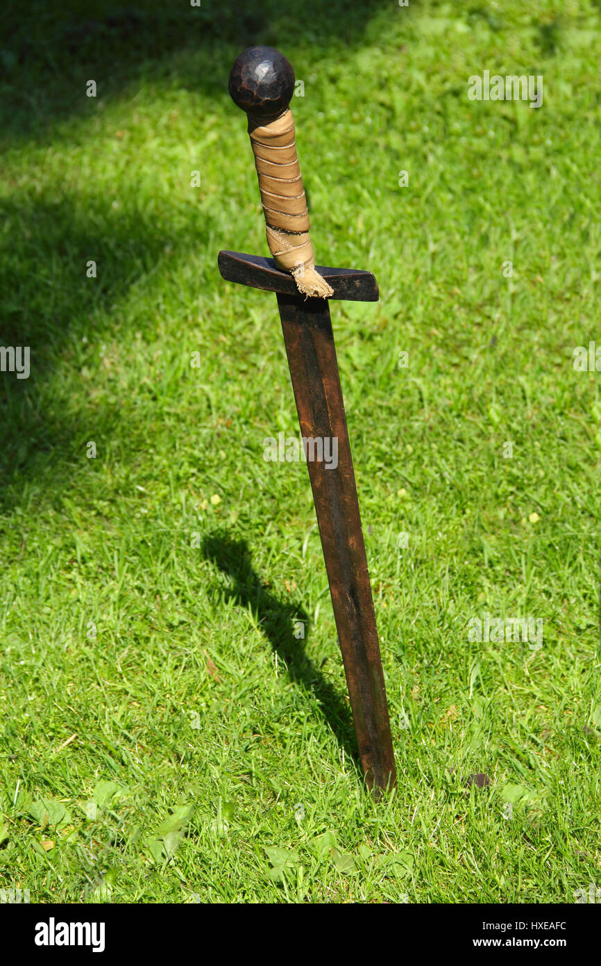 Old rusty sword on green grass background Stock Photo - Alamy