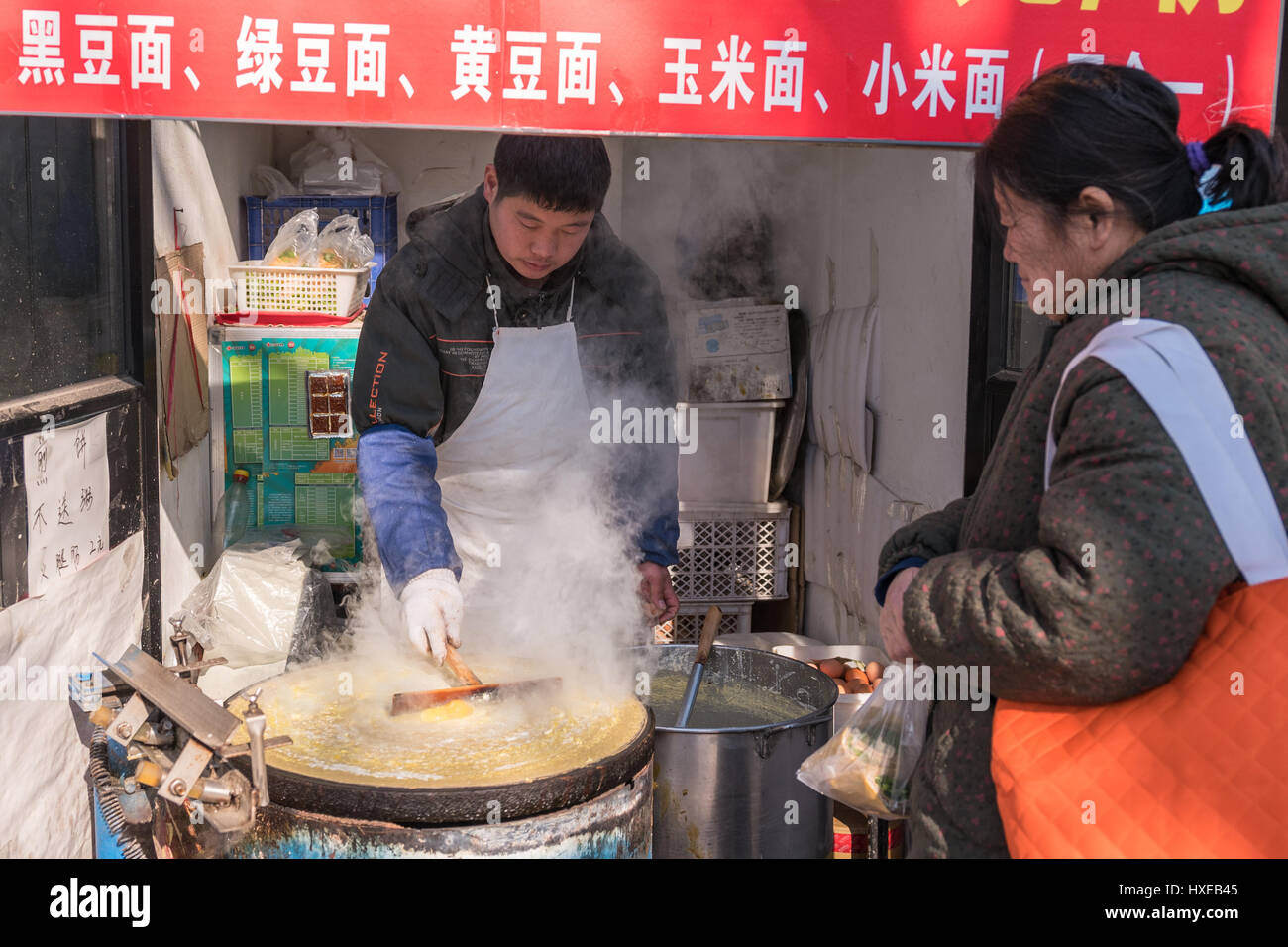 Street vendor making and selling Chinese pancakes in Beijing, China ...
