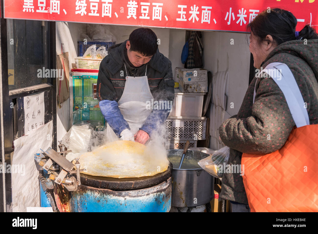 Street vendor making and selling Chinese pancakes in Beijing, China ...