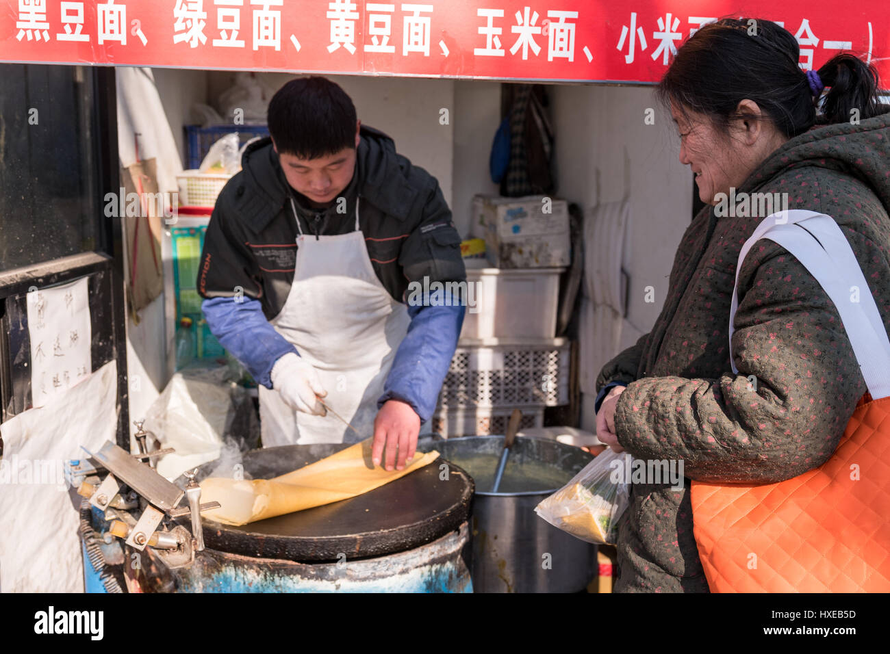 Street vendor making and selling Chinese pancakes in Beijing, China ...