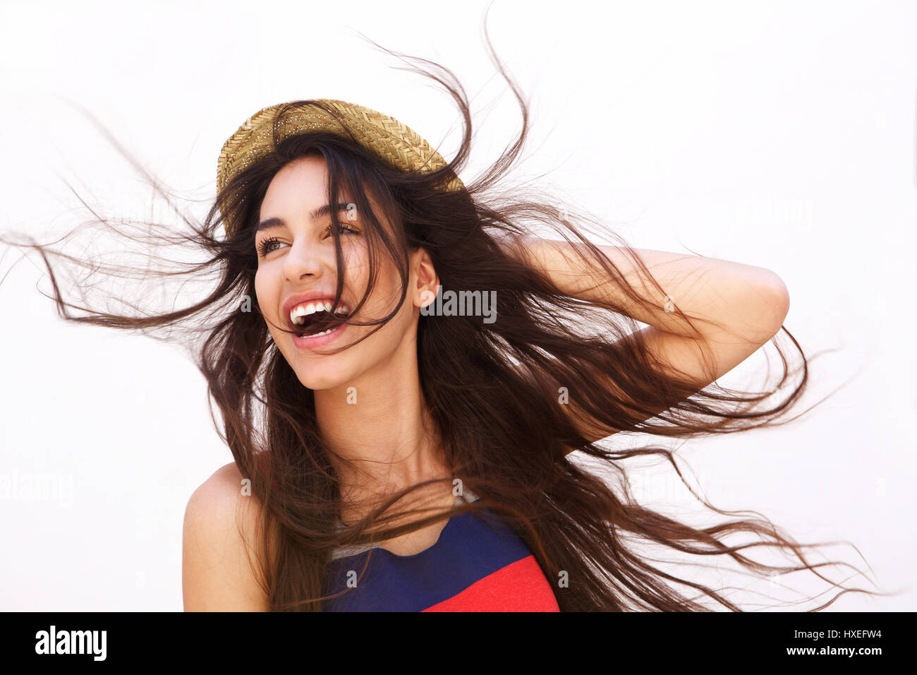 Portrait of a smiling young woman with long hair blowing in the wind ...