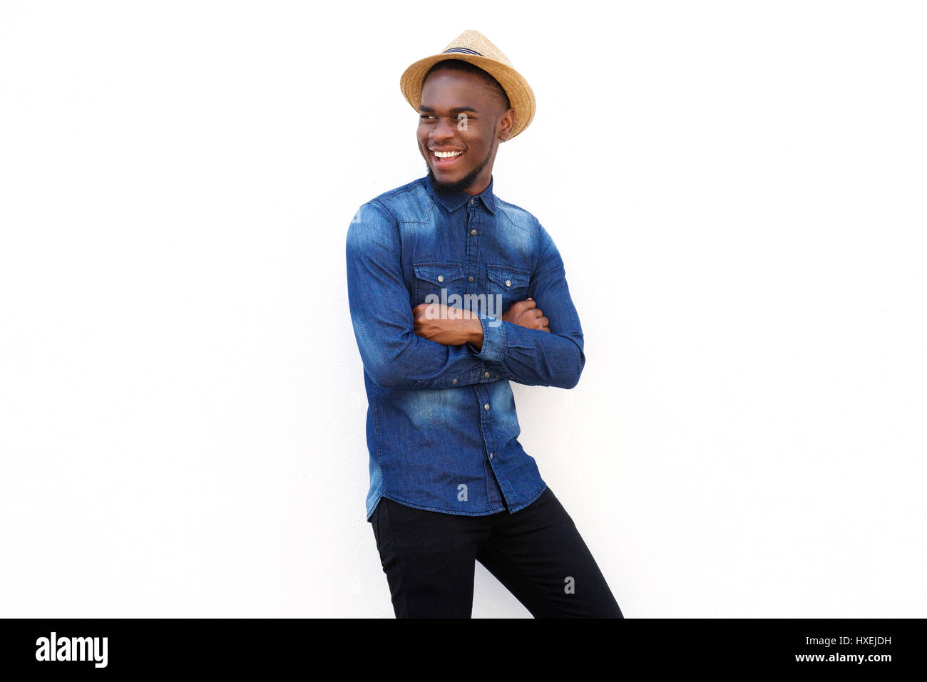 Portrait of a happy young modern man standing with arms crossed against ...