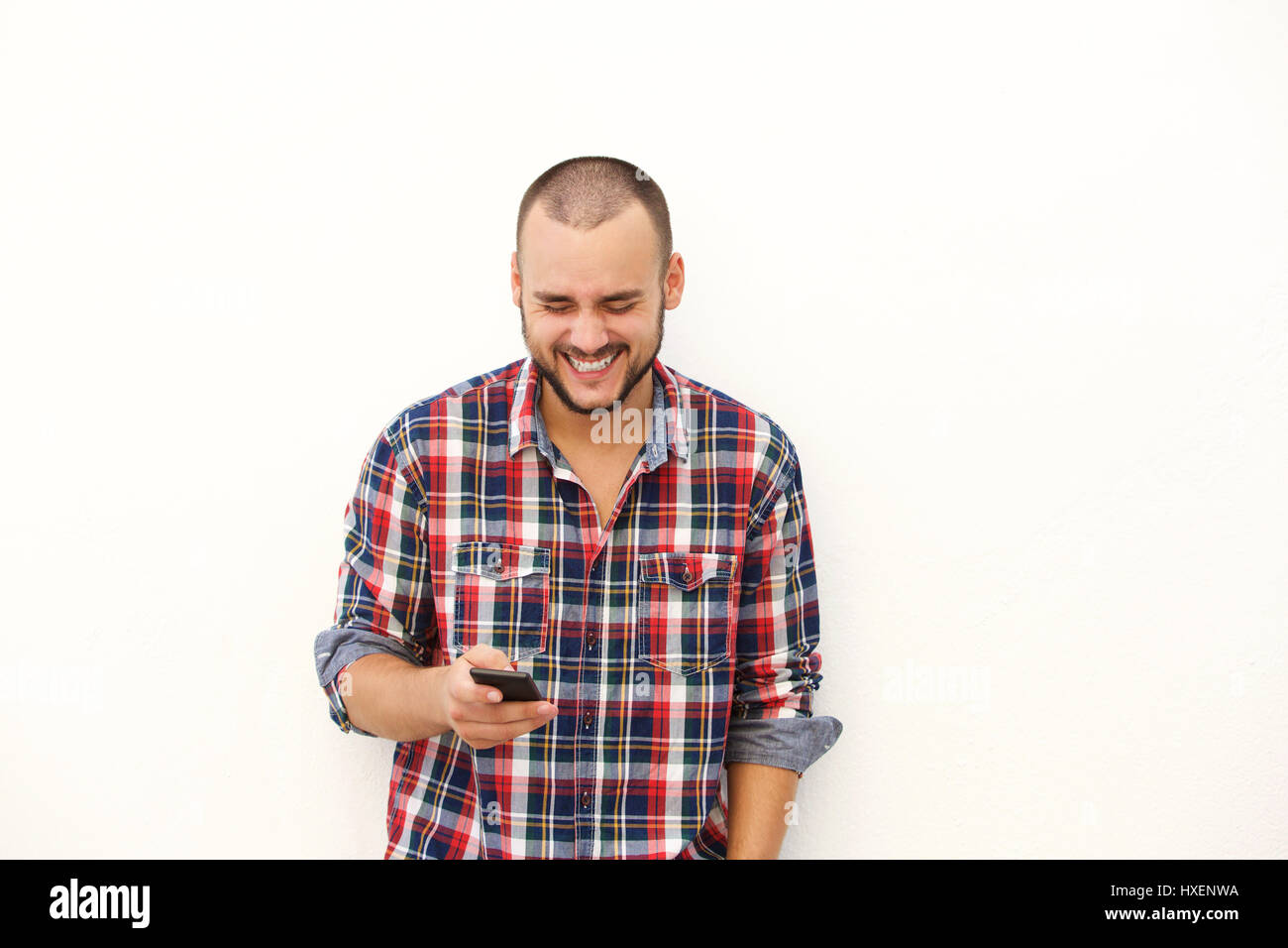 Portrait of a happy man laughing after reading text on mobile phone ...