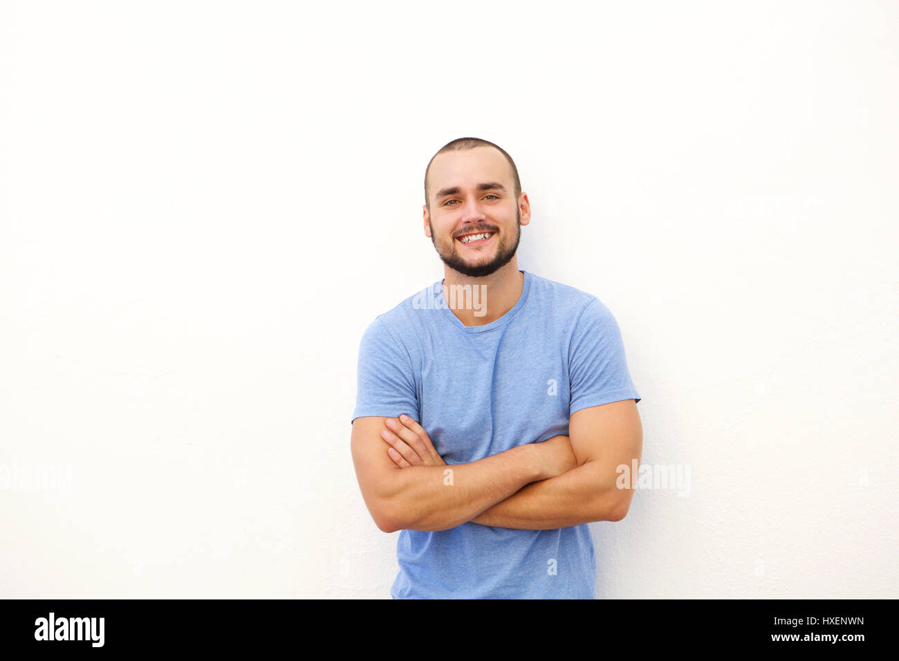 Charming young man smiling against white background with arms crossed ...