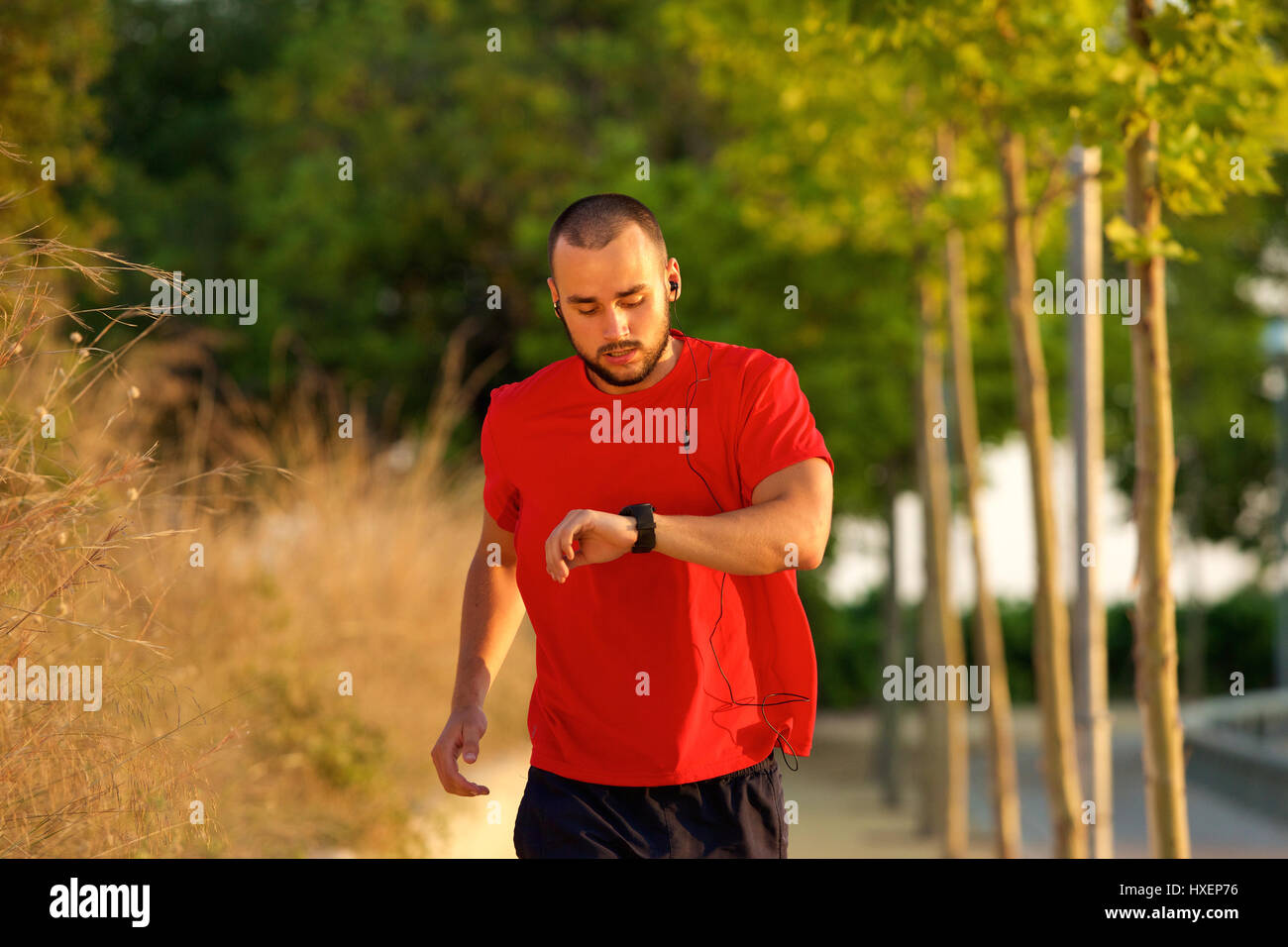 Active young man running outdoors checking time on watch Stock Photo ...