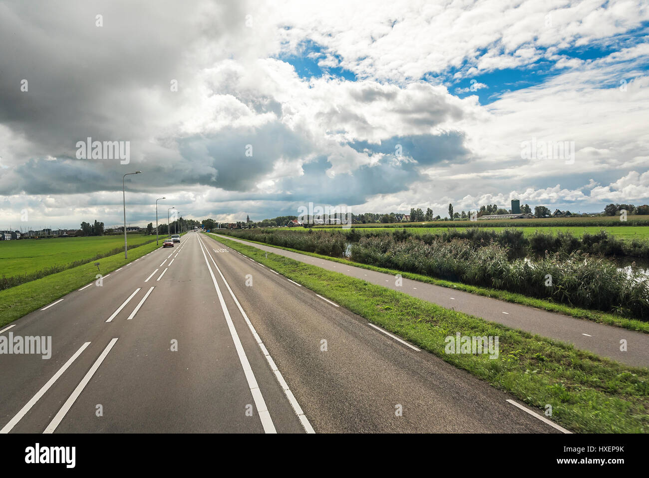 Country road with beautiful markings, against a contrasting cloudy sky ...