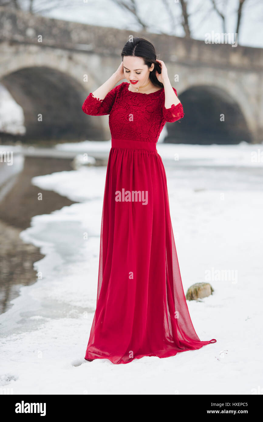 Women in red dress standing in the snow Stock Photo - Alamy