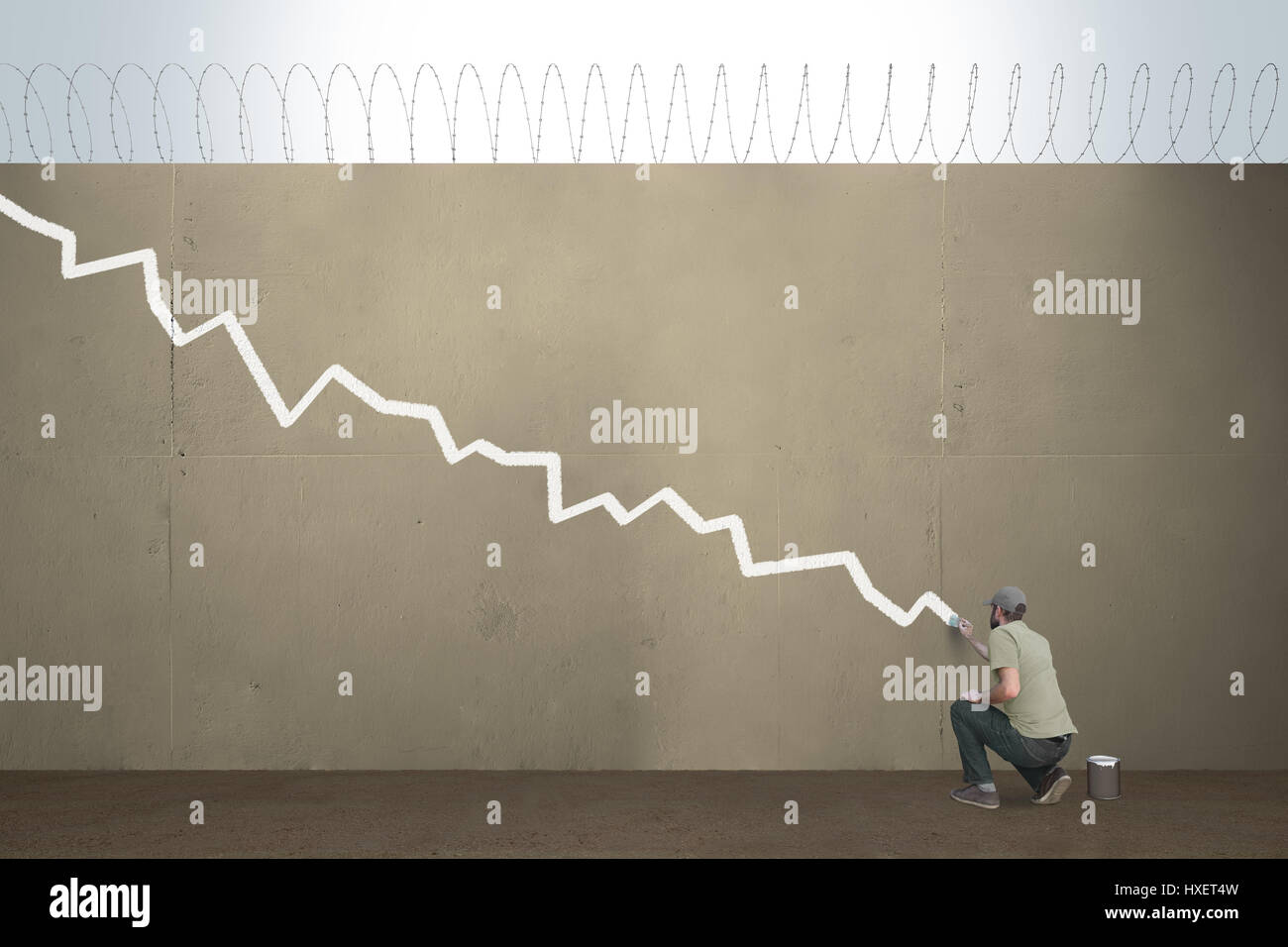 A man draws a falling chart on a border barrier Stock Photo - Alamy