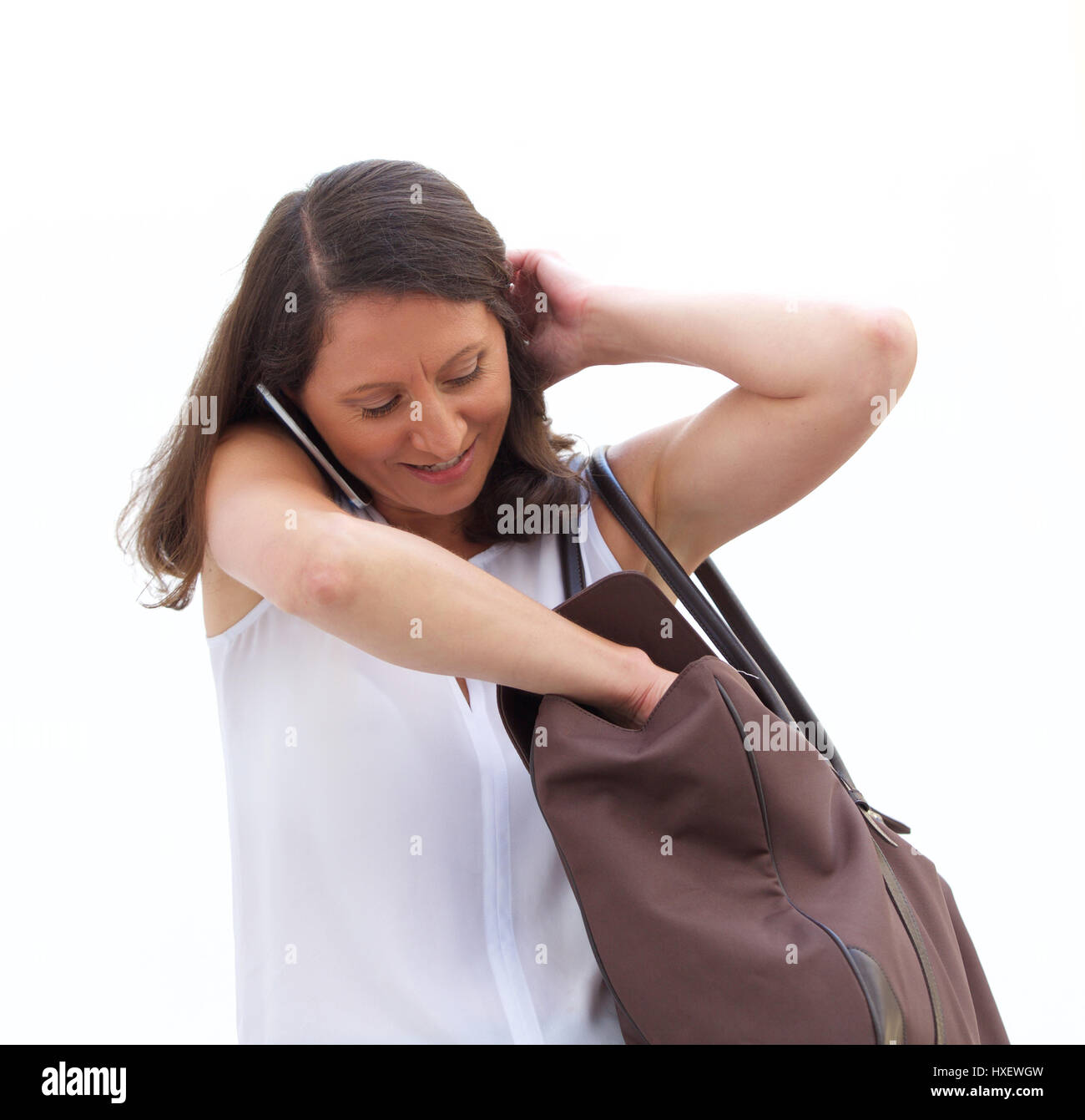 Portrait of a woman searching through handbag while talking on mobile ...