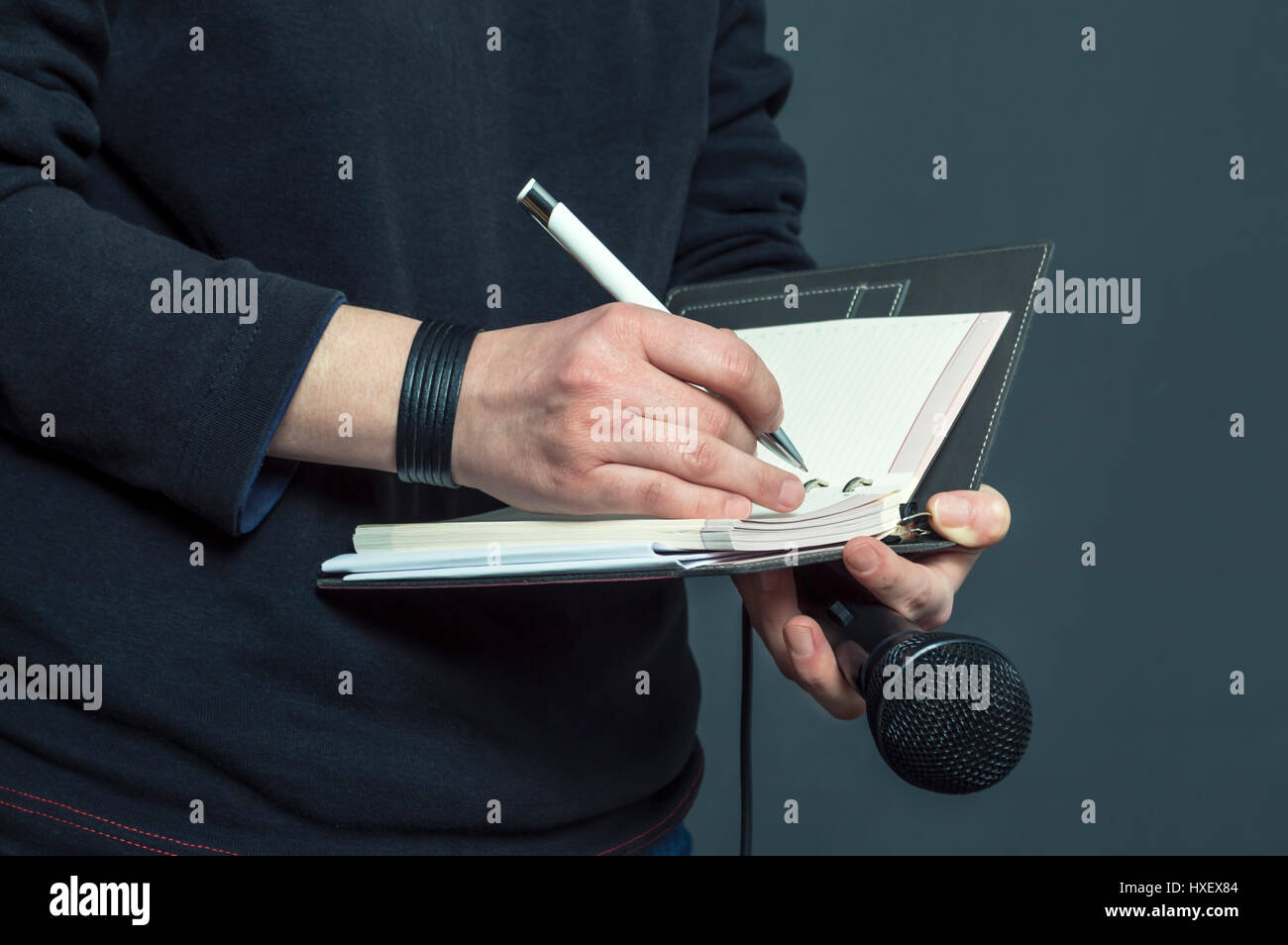 Journalist at press conference, writing notes, holding microphone ...