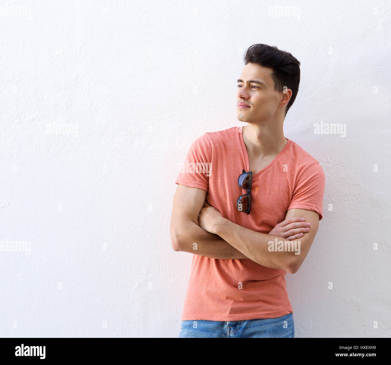 Portrait of a cool young guy posing with arms crossed against white ...