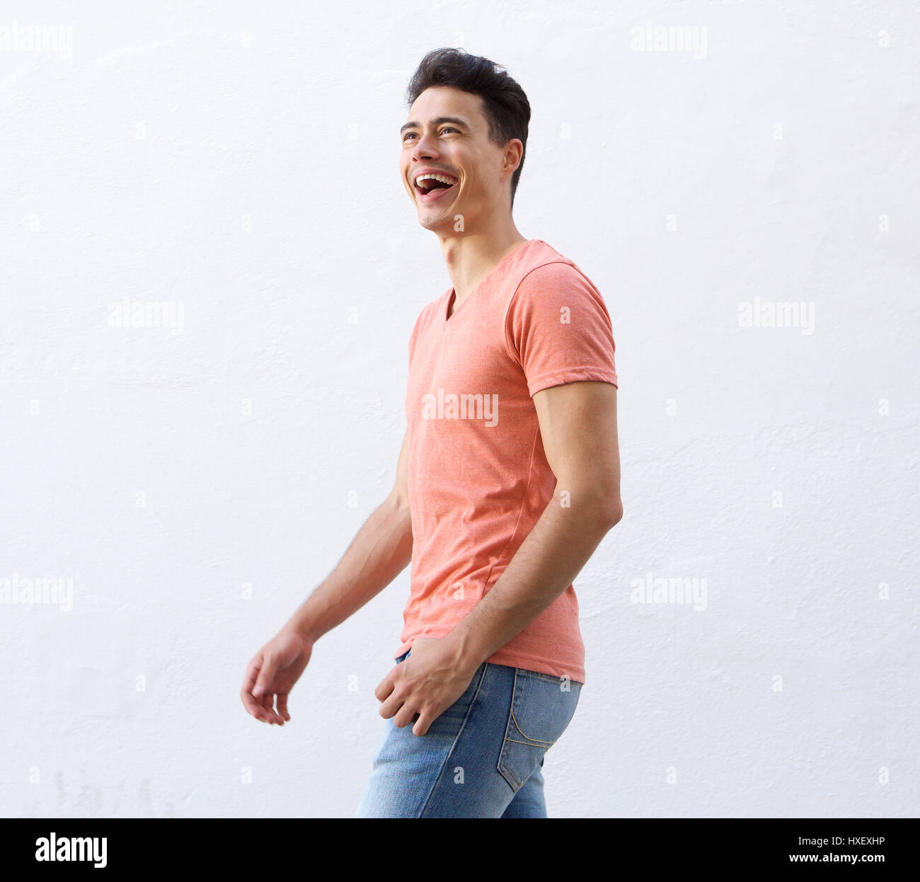 Side portrait of a cool guy walking and laughing against white ...