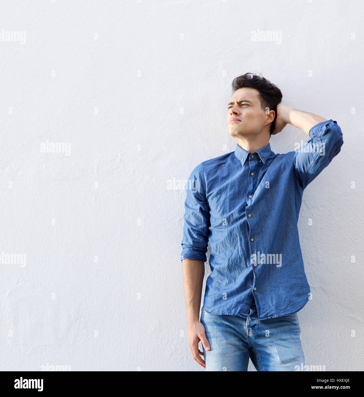 Portrait of a male hipster posing with hand in hair against white ...