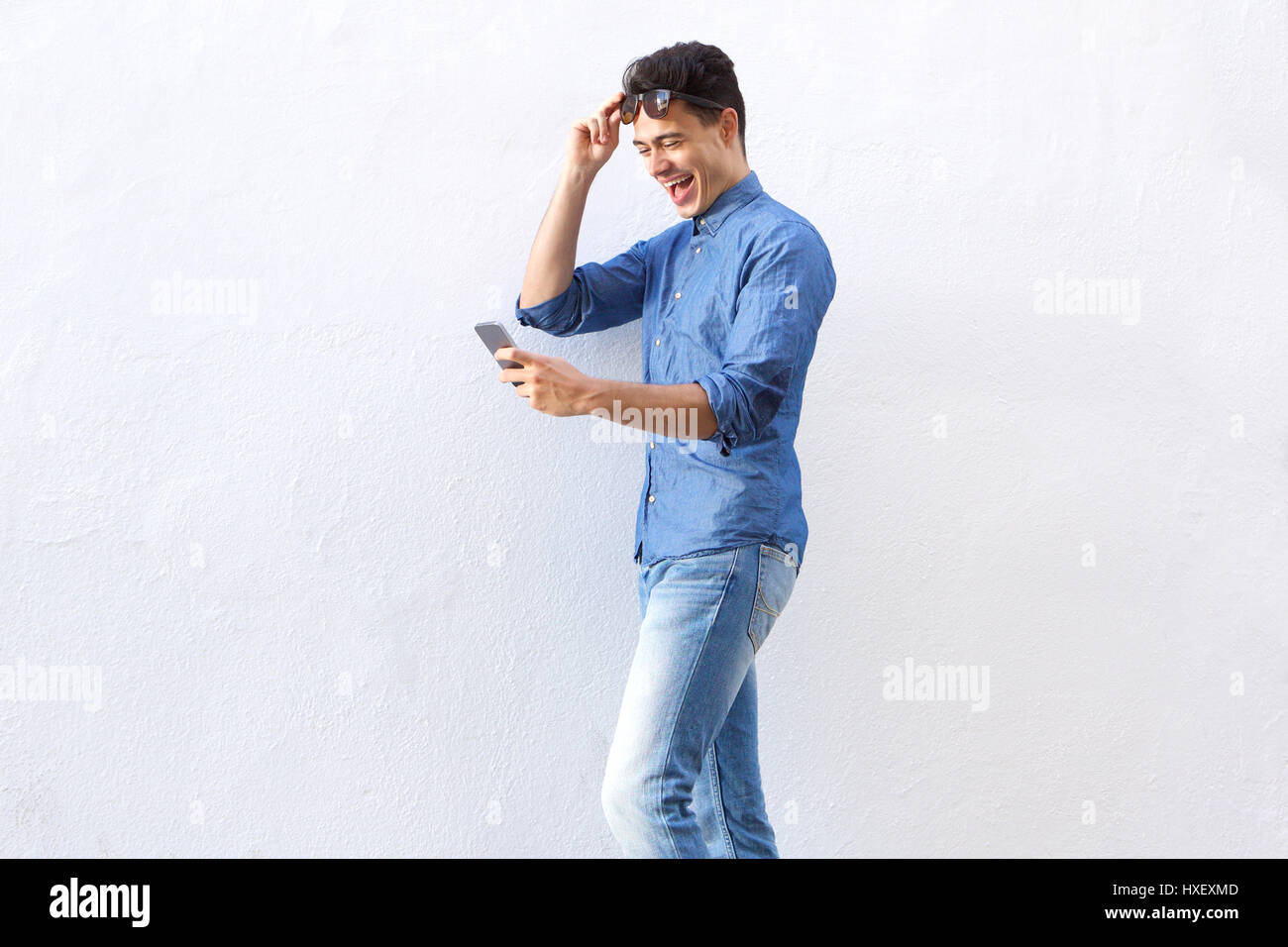 Portrait of a cheerful young man walking and reading text message on ...