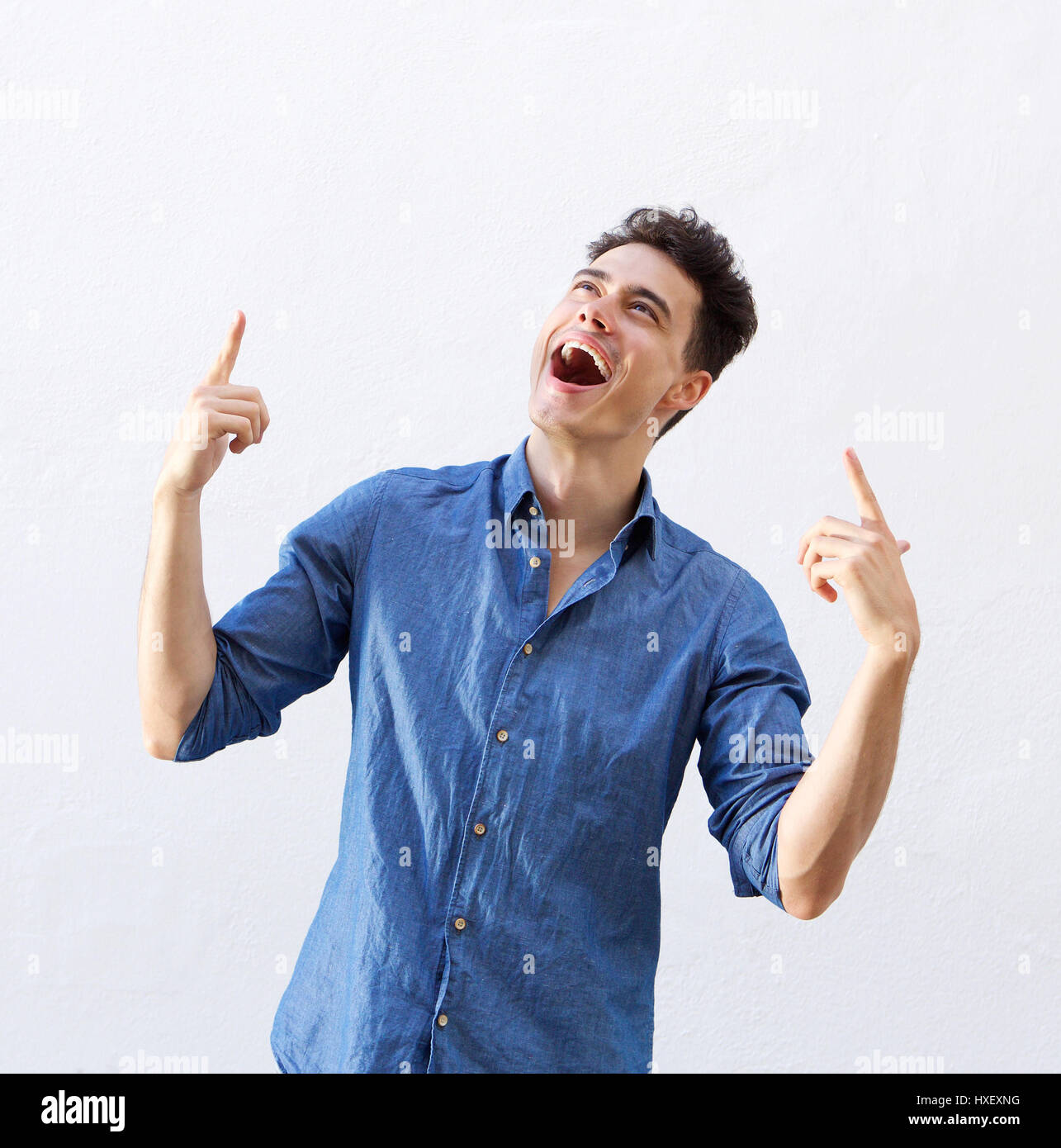Portrait of a cheerful young man pointing fingers to copy space on ...
