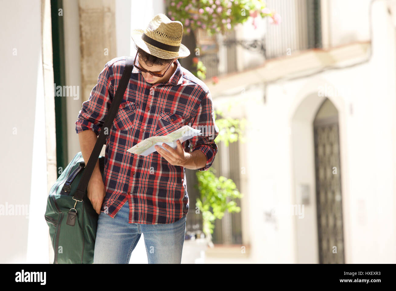 Portrait of a young traveling man walking with map and bag Stock Photo ...